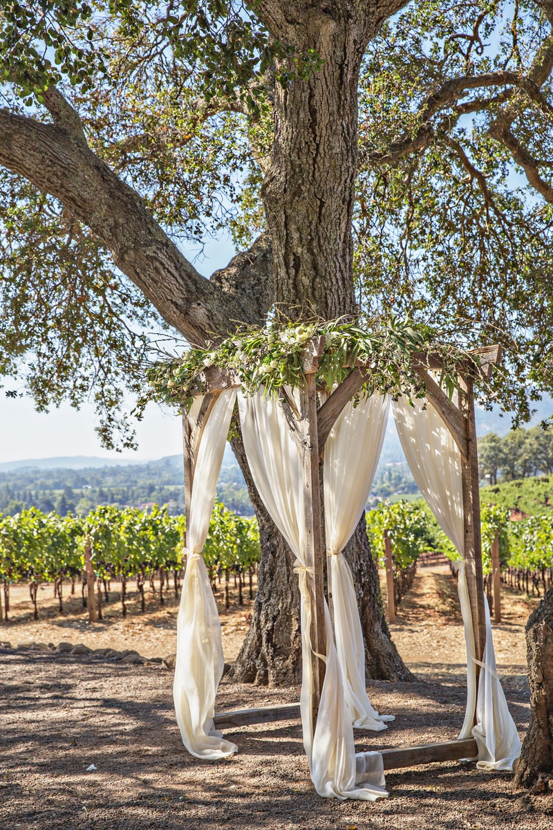 Ceremony Décor Photos - Small Wood Arbor with Drapery - Inside Weddings