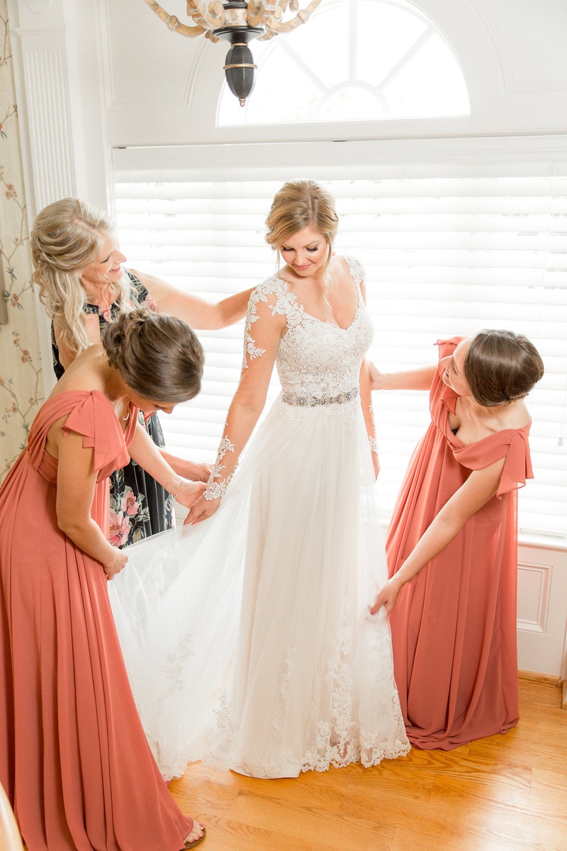 Wedding Dresses Photos - Bridesmaids & Mom Helping Bride - Inside Weddings